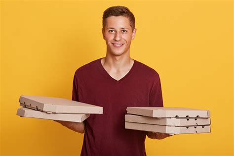 배달 개념입니다 잘 생긴 백인 피자 배달 남자의 클로즈업 초상화 노란색 스튜디오 배경 위에 고립 된 포즈 Bpth 손에 남성 홀징 피자 상자 카메라를보고 캐주얼 착용