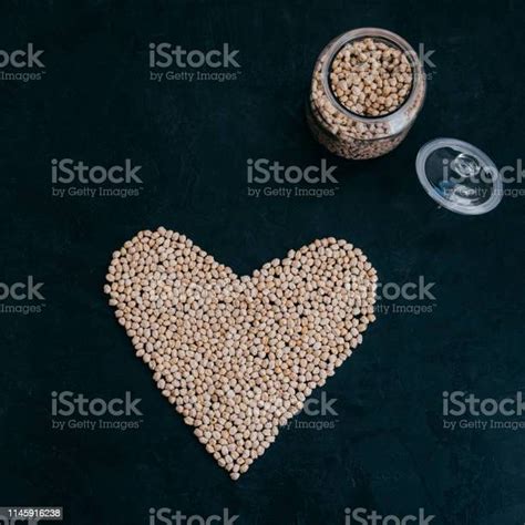 유리 항아리에 마른 깨끗 한 병아리 콩 유기농 생가 르 반 조로 만든 심장 검정색 배경입니다 식물 기반 단백질 건강 한 요리를