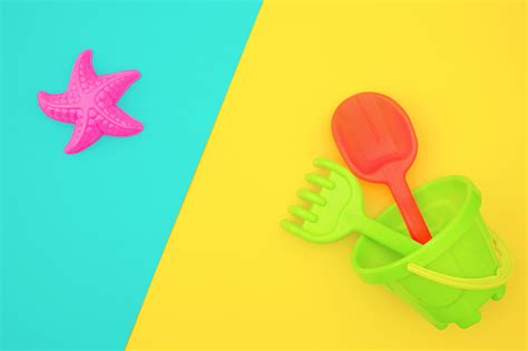 복사 공간이있는 파란색 노란색 배경의 모래 해변에서 모래 상자 또는 모래 해변에서 여름 게임을위한 여러 가지 빛깔의 어린이 장난감 탑 뷰 플랫 레이 컨셉 텍스트 또는