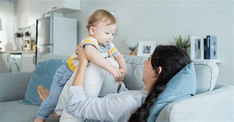 백인 사랑하는 엄마는 거실의 소파에서 아기 아이와 놀고 있습니다 행복한 가족 매력적인 아름다운 돌보는 젊은 어머니 들어