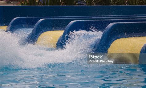 남자는 푸른 물 미끄럼에서 수영장으로 큰 속도로 날아갔고 강한 스프레이를 남겼습니다 워터 파크의 다중 줄 블루 및 옐로우 워터 슬라이드 0명에 대한 스톡 사진 및 기타