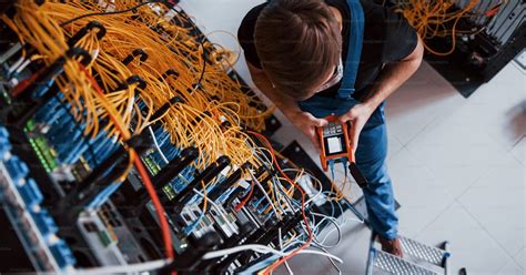 서버 룸에서 인터넷 장비 및 전선으로 작동하는 측정 장치가 있는 제복을 입은 청년의 상위 뷰 사진 Unsplash의 우크라이나 이미지