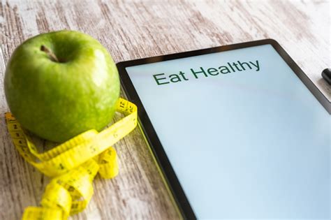 균형 잡힌 식단 체중 감량 및 영양 목표를 위한 건강하게 먹기 개념을 표시하는 측정 테이프와 태블릿이 있는 녹색 사과 0명에