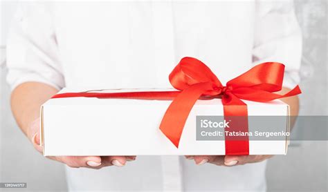 빨간 활이 달린 흰색 선물 상자를 들고있는 여성 손의 클로즈업 여자는 빨간 리본이 달린 흰색 상자를 들고 있습니다 기념일에 대한 스톡 사진 및 기타 이미지 Istock