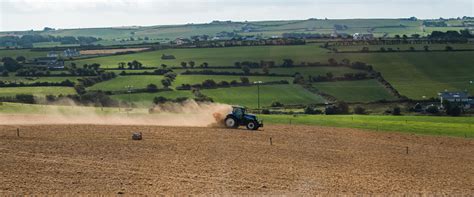아일랜드 웨스트 코크 2022년 8월 20일 아일랜드의 여름날 파란 트랙터가 쟁기질 된 밭에 씨를 뿌린다 아일랜드 농장에서의 농업 작업 농업 경관 현장의 트랙터 0명에 대한