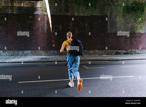 Non Binary Person With Backpack Running On Road Stock Photo Alamy