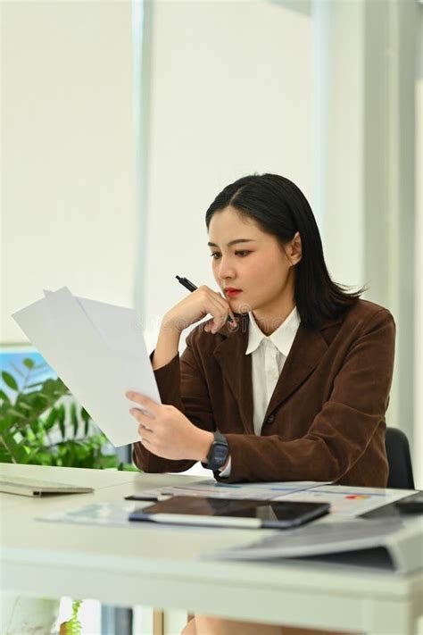 Focused Millennial Female Manager Preparing Report And Analyzing Work Results At Office Desk