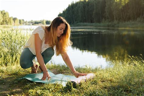 요가 야외에서 연습하는 예쁜 젊은 여성 해변에서 운동을위한 요가 매트를 압연 슬림 피트니스 여성 아름다운 요기 여자는 자연에서 훈련하려고합니다 건강한 라이프 스타일 개념