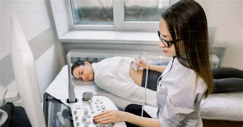 전문 여성 초음파 Therapist 클리닉에서 초음파 기계로 작업하고 여성 환자를위한 신장 초음파를 만들고 화면을보고 제어판의 버튼을 누르고 있습니다 사진