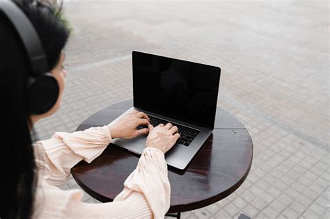 손에 Vitiligo 피부 색소 침착을 가진 여자는 온라인 노트북에서 일하고 카페에서 야외에서 헤드폰으로 음악을 듣습니다 피부 계절성 질환 30 34세에 대한 스톡 사진 및