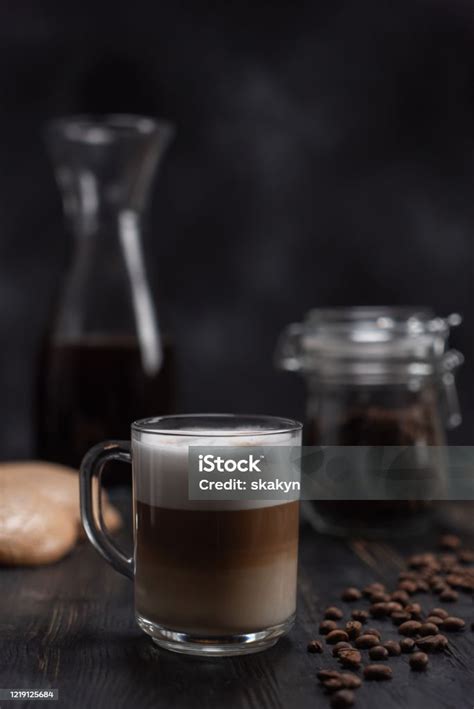 투명 한 커피 카푸치노 또는 라떼 컵 쿠키와 커피 콩의 항아리 옆에 검은 테이블에 검은 색 나무 테이블 검은 배경에 계피와 커피 콩커피 카푸치노 또는 라떼 한 잔 0명에