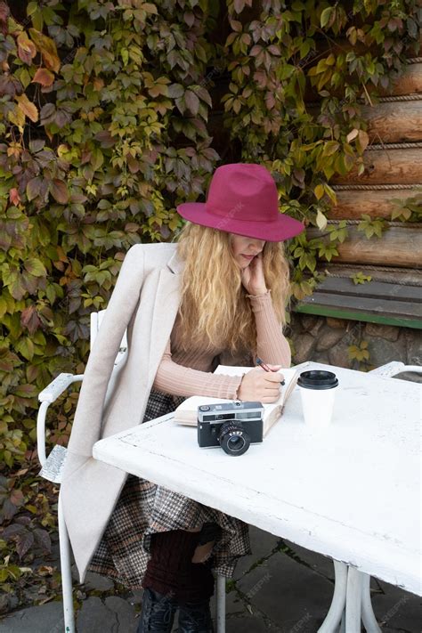 Une Fille Au Chapeau Bordeaux Est Assise à Une Table Dans Un Café De