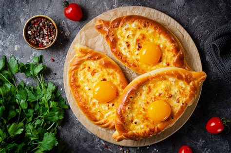 치즈로 속을 채우고 달걀 노른자를 얹은 Ajarian Khachapuri 어두운 배경에 전통적인 조지아 Khachapuri 계란