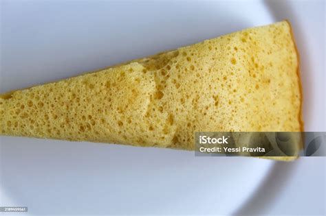 인도네시아 메단의 전통 케이크인 비카 암본 한 조각 타피오카 가루 계란 설탕 효모 및 코코넛 밀크로 만들어졌습니다 흰색 배경에 고립되어 있습니다 플랫 레이 또는 평면도 0