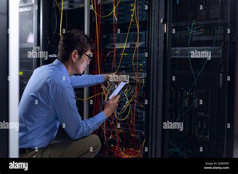 asian male engineer using digital tablet and inspecting computer server