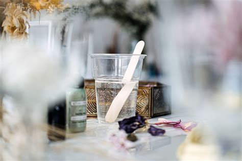 투명한 플라스틱 컵에 나무로 된 교반 막대기가 있는 수지를 섞어 말린 꽃과 공예 재료로 둘러싸여 있습니다 Diy 아트 프로젝트 친환경 가정 장식 지속 가능성 30 34세에