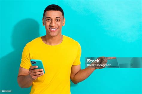 젊은 남자 프로모터 착용 트렌디 한 티셔츠의 사진은 손가락 모형 빈 공간 전화 Estore 광고 아쿠아 마린 색상 배경에 고립 Brand Name Smart Phone에