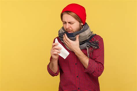 모자를 쓰고 따뜻한 스카프를 입은 독감 에 걸린 남자 냅킨에서 재채기 인후통 고온으로 몸이 좋지 않은 느낌 25 29세에 대한 스톡 사진 및 기타 이미지 Istock