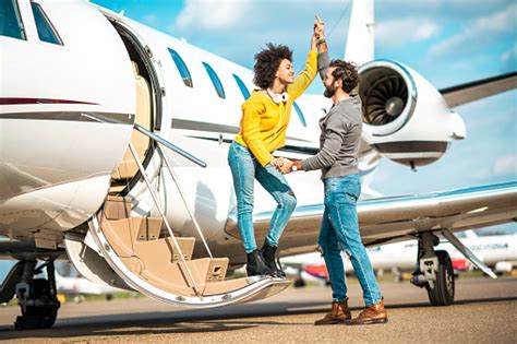 젊은 성공적인 부부는 손을 잡고 공항 활주로에 주차 된 개인 비행기 옆에 함께 춤을 추고 있습니다 2명에 대한 스톡 사진 및 기타 이미지 Istock