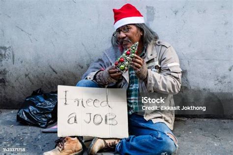노숙자 노인 아시아 남자가 벽 옆에 혼자 앉아 웃고 마시며 도움을 청하는 표지판을 들고 있습니다 미친 사람은 길가에 홀로 앉아 웃고 웃었다 60 64세에 대한 스톡 사진 및