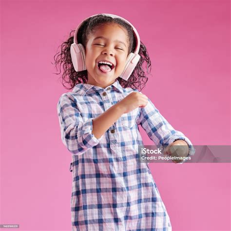 스튜디오에서 분홍색 카피 스페이스 배경에 헤드폰을 착용하면서 곱슬 머리로 음악을 듣는 예쁜 작은 혼합 경주 소녀 아프리카 어린이 춤과 자유로운 느낌 개발에 대한 스톡 사진