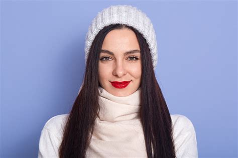 자기 매력적인 젊은 검은 머리 여자의 이미지는 자신감 표정 모자 스웨터와 스카프를 입고 빨간 입술을 가지고 카메라를 직접 보고 사람과 감정 개념 갈색 머리에 대한 스톡 사진