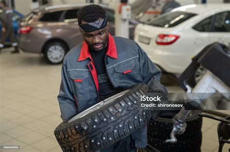 아프리카 인종의 젊은 수리인은 바퀴를 들고 그것을 변경하려고하는 동안 기술자에 대한 스톡 사진 및 기타 이미지 기술자 자동차 수리 공장 20 24세 Istock