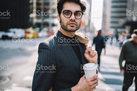 트렌디 한 정장 착용에 잘 생긴 자신감 사업가의 절반 길이 초상화 가서 커피와 함께 거리에 서 맨해튼에서 시간을 보내는 카메라를보고 우아한 정장과 안경을 자랑 Ceo 거리에