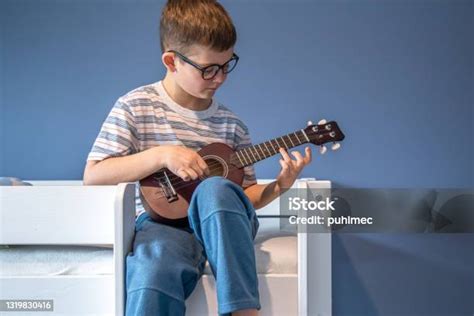 집 복사 공간에서 침대에 앉아 우쿨렐레를 연주하는 어린 소년 6 7 살에 대한 스톡 사진 및 기타 이미지 6 7 살 가정 생활 가정의 방 Istock