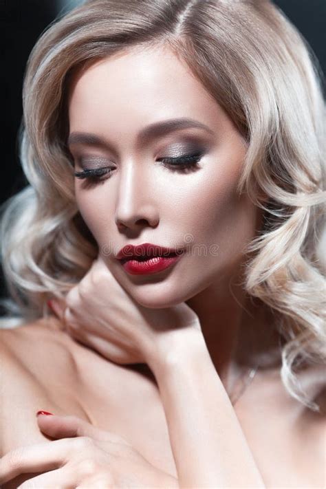 Молодая красивая блондинка сидит на окне в сером свитере Стоковое Фото изображение