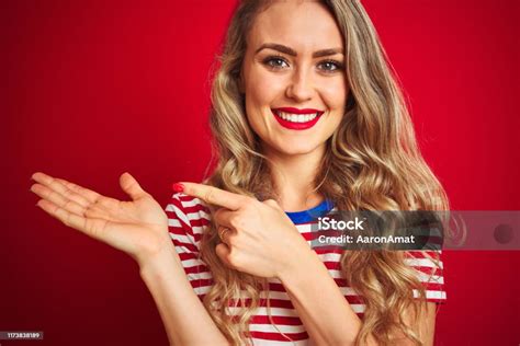 젊은 아름다운 여자 를 입고 줄무늬 T 셔츠 서 위에 서 빨간 고립 된 배경 매우 행복 가리키는 손과 손가락 T 셔츠에 대한 스톡 사진 및 기타 이미지 Istock