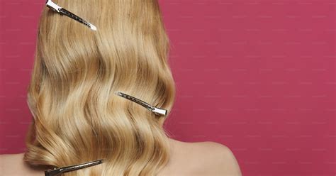 아름다움과 헤어 스타일 물결 모양의 자물쇠에 바렛 악어 클립이 있는 젊은 벌거벗은 금발 여성의 초상화를 닫습니다 분홍색으로