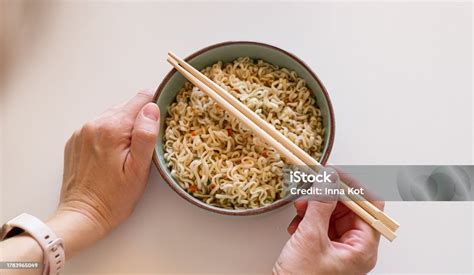 손은 젓가락을 사용하여 흰색 배경에 증기로 맛있는 국수를 집어 들고 선택적 초점을 맞춥니다 평면도 테이블 위의 아시아 식사 정크 푸드 컨셉 가정 주방에 대한 스톡 사진 및