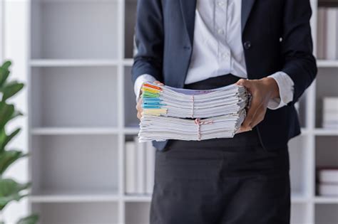 비즈니스 직원 아시아 여성은 바쁜 작업 책상 직장 사무실에서 폴더 용지에 미완성 문서 아카이브를 검색하고 확인하기 위해 종이 파일을 쌓습니다 비즈니스 문서 개념입니다