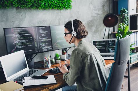 Young Female Programmer Working At Office Desk With Multiple Screens
