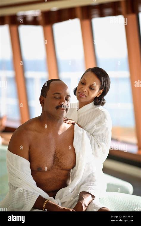 Woman Giving Her Husband A Shoulder Massage In Spa Treatment Room