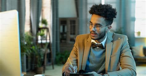 테이블에 앉아 컴퓨터 모니터를 보고 있는 젊은 사업가는 온라인 비즈니스 회의 중에 메모를 하고 있다 사진 Unsplash의 실업가 이미지