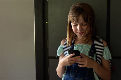 스마트 폰을 사용하여 복도에서 사물함에 기대어 여학생 개발에 대한 스톡 사진 및 기타 이미지 개발 고등학교 교육 Istock