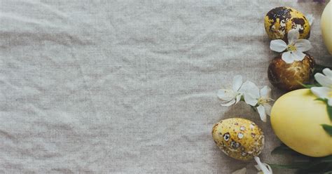 소박한 린넨 배경에 봄 꽃이 있는 부활절 달걀 텍스트를 위한 공간이 있는 평평한 누워 세련된 현대 부활절과 천연 염료와 봄 꽃이 피는 메추라기 달걀 미적 계절 인사말