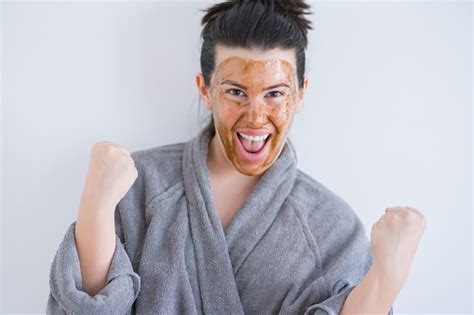 미용 페이셜 마스크를 착용한 아름다운 젊은 여성이 눈을 뜨고 눈을 뜨고 성공을 축하하고 놀라움을 자하는 스킨 케어 뷰티 트리트먼트로 우승자 컨셉 갈색 머리에 대한 스톡 사진