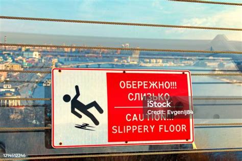 기호에 텍스트 주의 미끄러운 바닥 떨어지는 남자의 흰색 텍스트와 실루엣 직사각형 빨간색과 흰색 접시 배경의 흐릿한 도시 경관