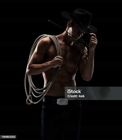 셔츠를 입고 카우보이 모자를 쓰고 올가미를 들고 검은 배경에 청바지를 입고 장미를 들고있는 잘생긴 남자 20 24세에 대한 스톡 사진 및 기타 이미지 Istock