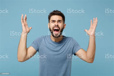 파란 배경 스튜디오 초상화에 고립 된 포즈 캐주얼 옷을 입은 젊은 화가 남자를 충격에 빠뜨렸습니다 사람들은 진지한 감정 라이프 스타일 개념 복사 공간을 모의합니다 위를