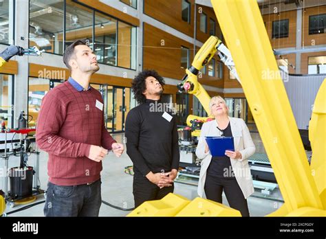 Group Of Engineers And Scientists Examining Multi Purpose Robotic Arms For Industrial