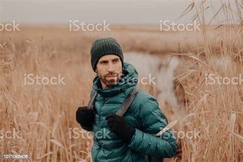 어두운 수염으로 잘생긴 젊은 남자의 총 운반 가방 보이는 뭔가 통지 사려깊은 식 야외에서 자유 시간을 보낸다 가 시간입니다 사람들 및 모험 개념 가을에 대한 스톡 사진 및