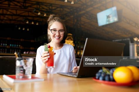 칵테일 혼혈 여자 손잡고 웃 고 노트북에서 작동 합니다 안경에서 사업 일 하는 동안 신체 수 분에 대 한 주스 음료 매력적인 디자이너 끄다의 갈증 건강 한 라이프 스타일