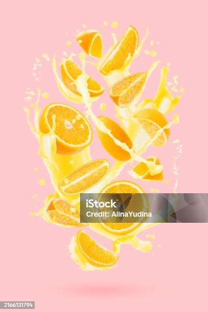 오렌지 주스 방울 스플래쉬 주스의 흐름과 오렌지 조각은 분홍색 배경에 공중 부양합니다 건강한 이국적인 과일 광고용 음료 라벨