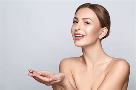 완벽 한 피부 초상화와 뷰티 스파 여자입니다 아름 다운 미소 갈색 스파 소녀 텍스트 손 손바닥에 빈 복사본 공간을 보여주는 제품을 제안합니다 광고에 대 한 제스처입니다 회색