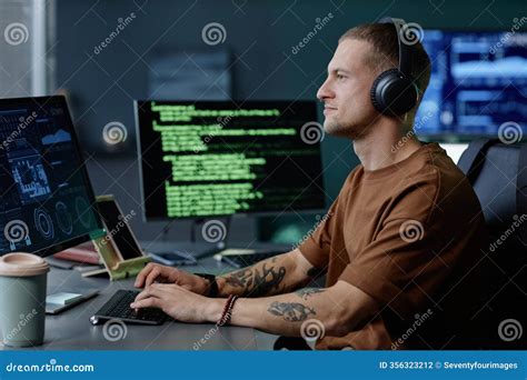 Male Programmer In Headphones Using Computer Working On Code