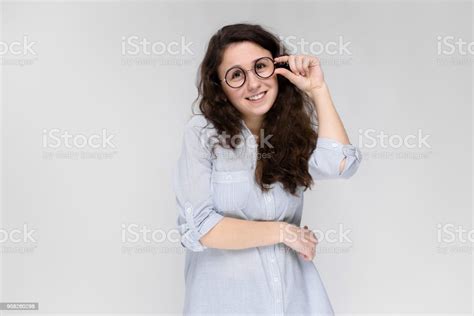 안경에 젊은 여자의 초상화입니다 회색 바탕에 아름 다운 어린 소녀입니다 가벼운 블라우스와 검은 바지에 젊은 여자 갈색 머리에